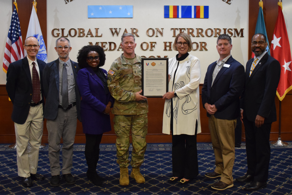 People posing and holding a signed document