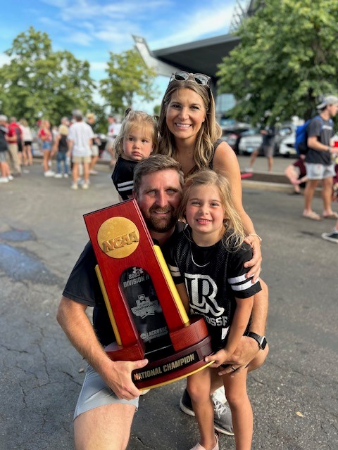 Justin Hay holding a trophy surrounded by his wife and two daughters